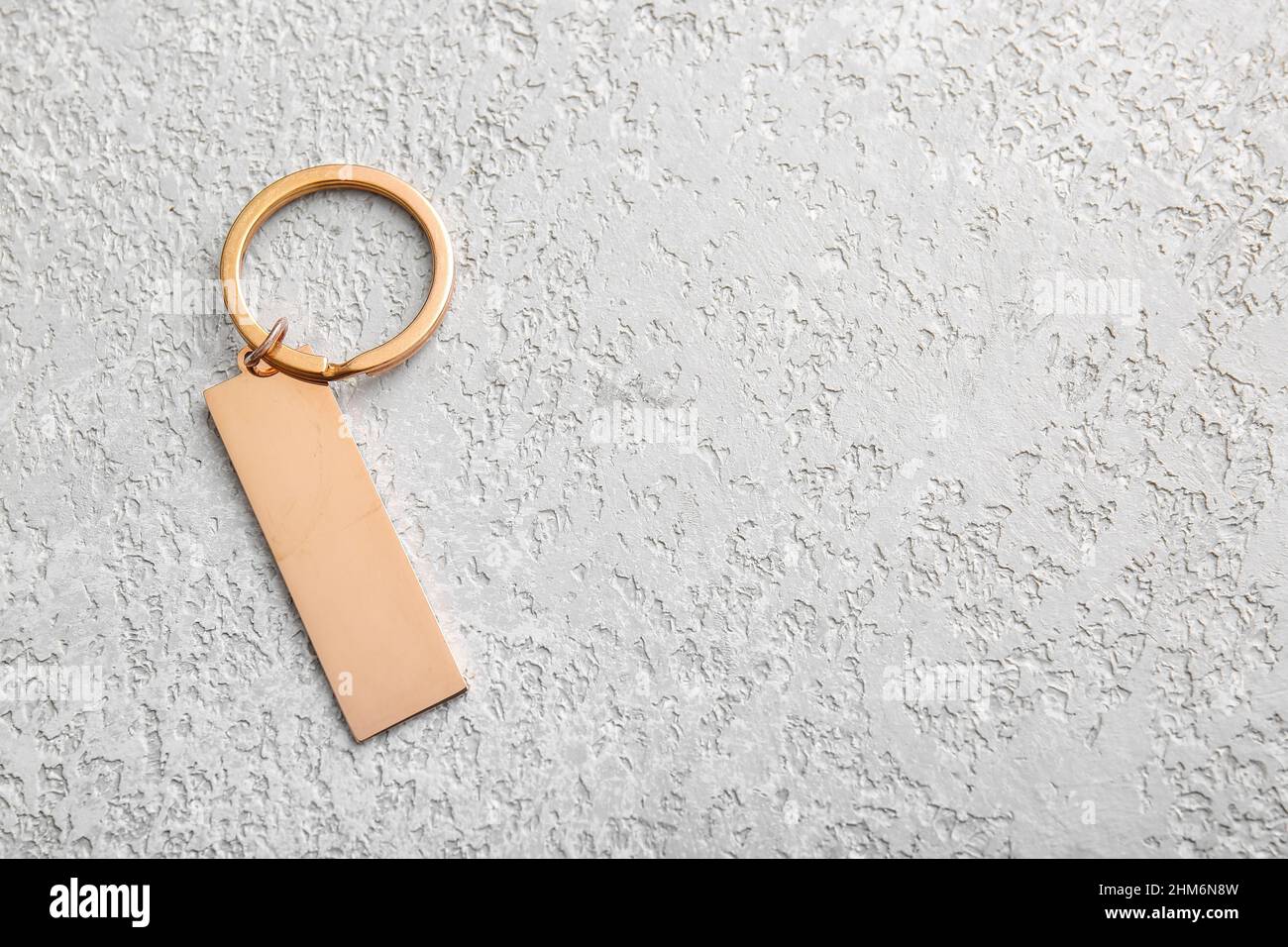 Stylish bronze keychain on light background Stock Photo - Alamy