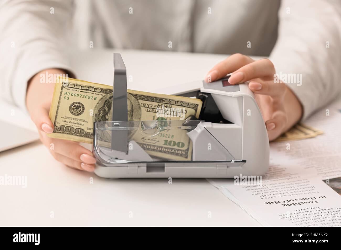 Female accountant using currency counting machine on light table Stock ...