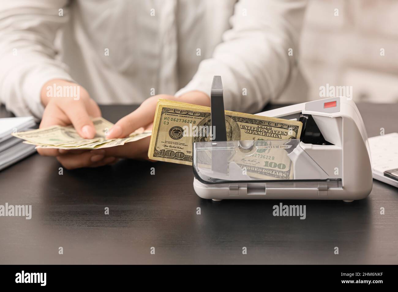 Female accountant with money and currency counting machine on dark ...