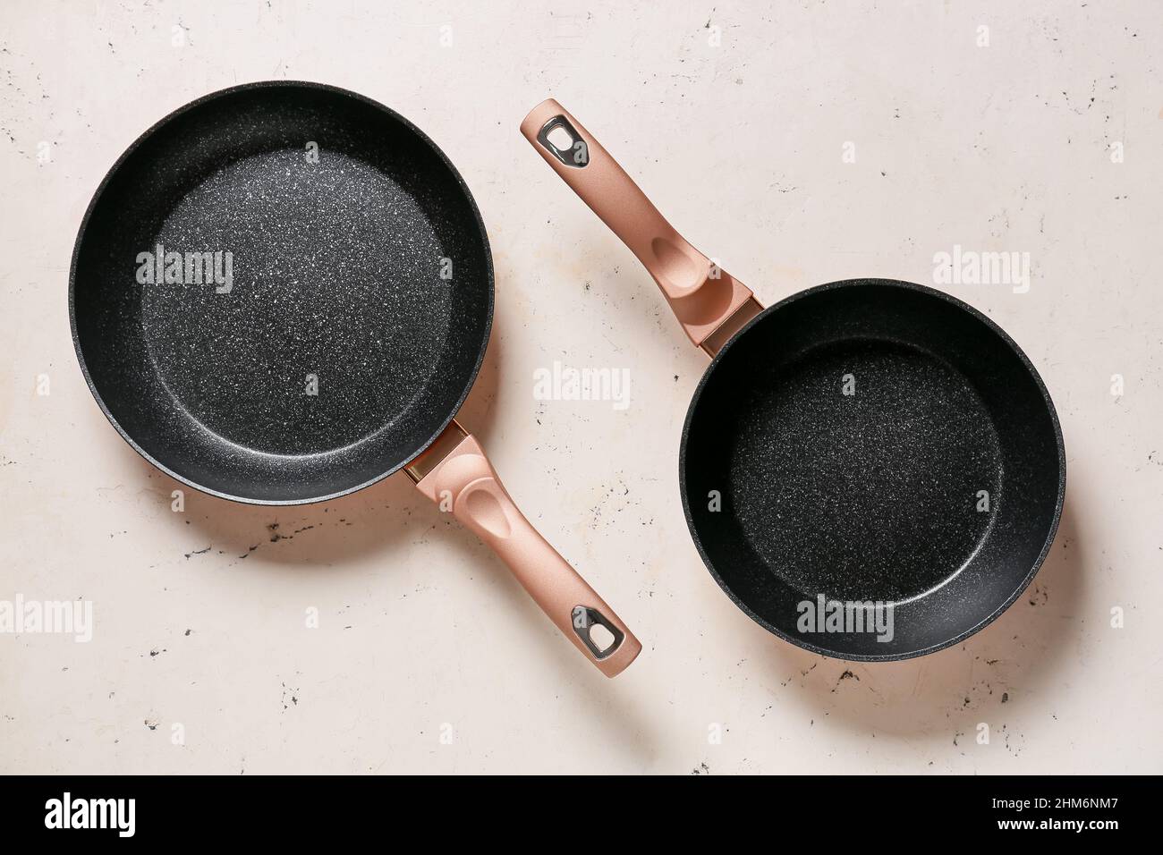 Frying pans on light background Stock Photo - Alamy