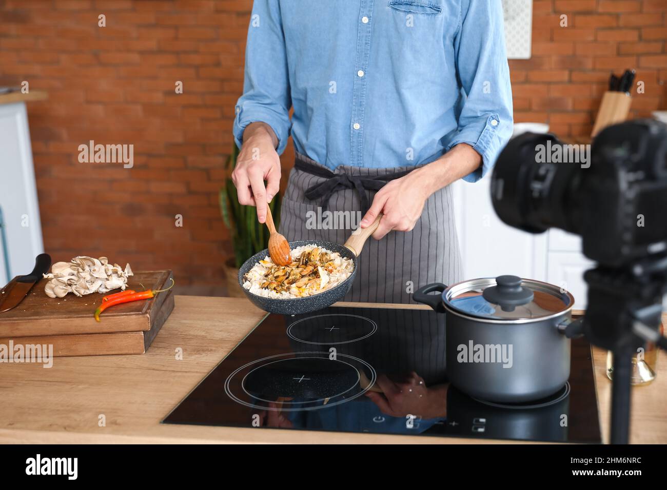 Young man cooking tasty rice while recording video tutorial in kitchen ...