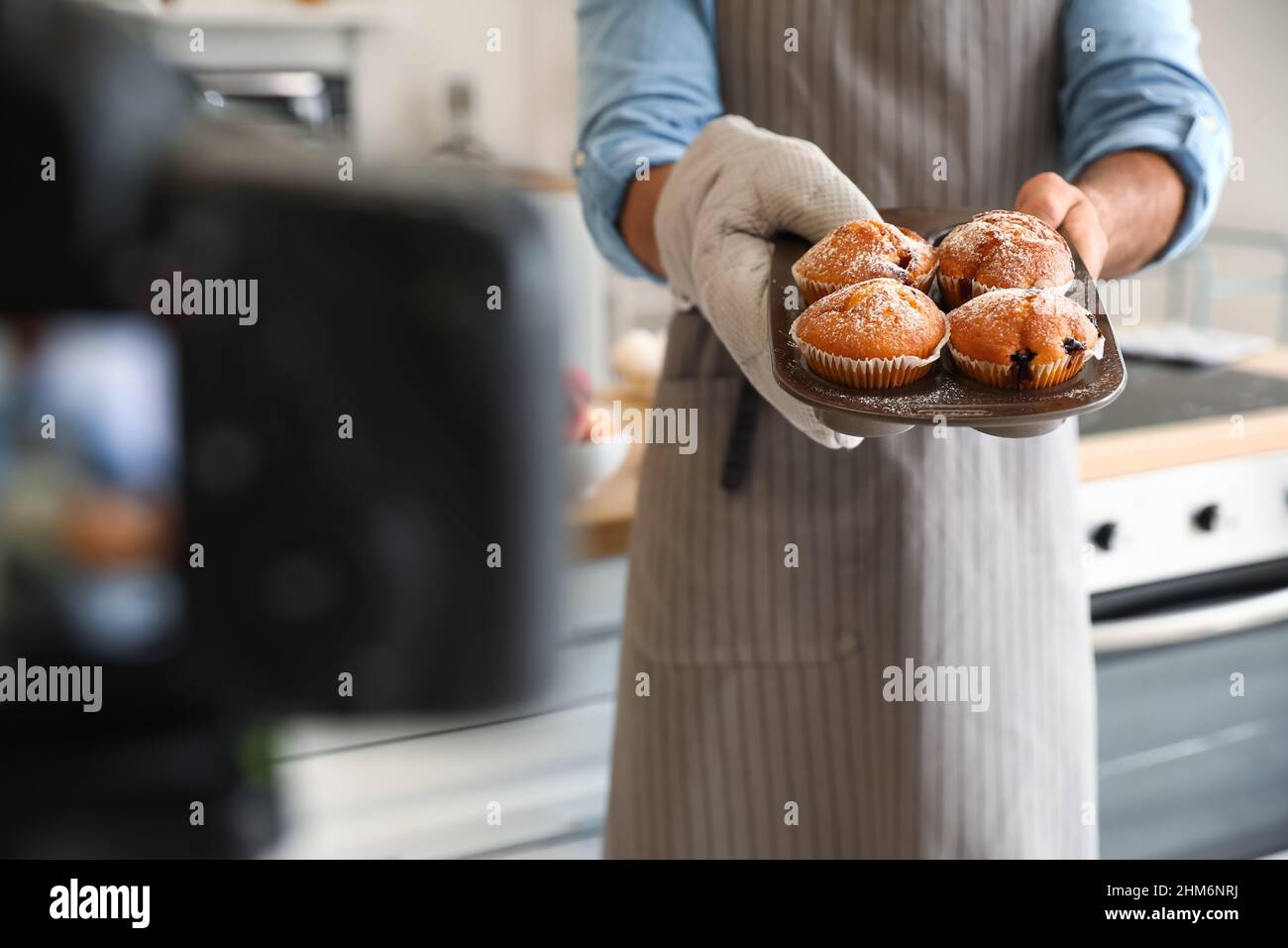 Handsome man with peach muffins recording video in kitchen, closeup ...
