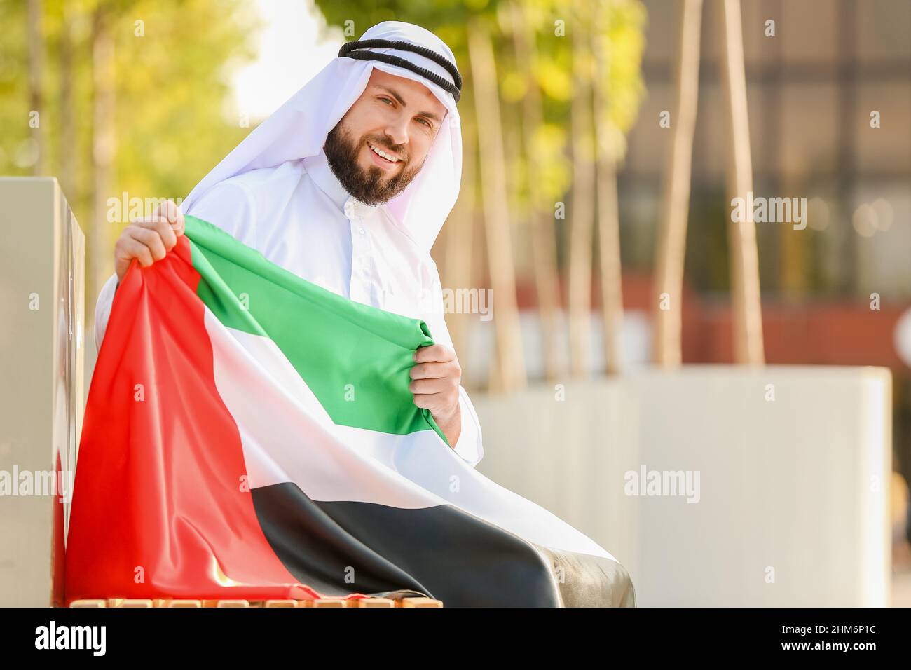 Handsome Muslim man with UAE flag sitting on bench outdoors Stock Photo ...
