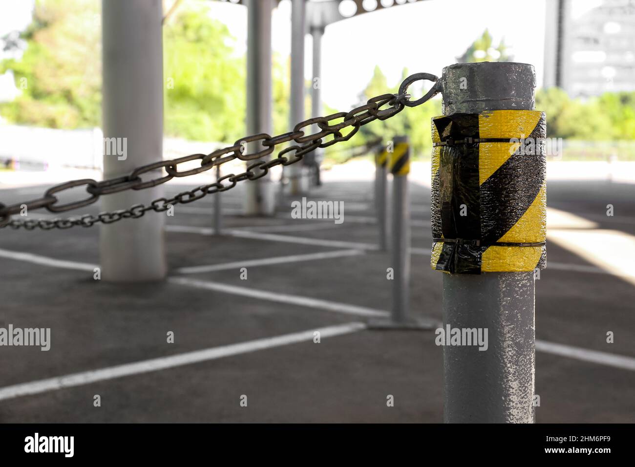 Parking limiters with chain on parking lot under canopy Stock Photo - Alamy