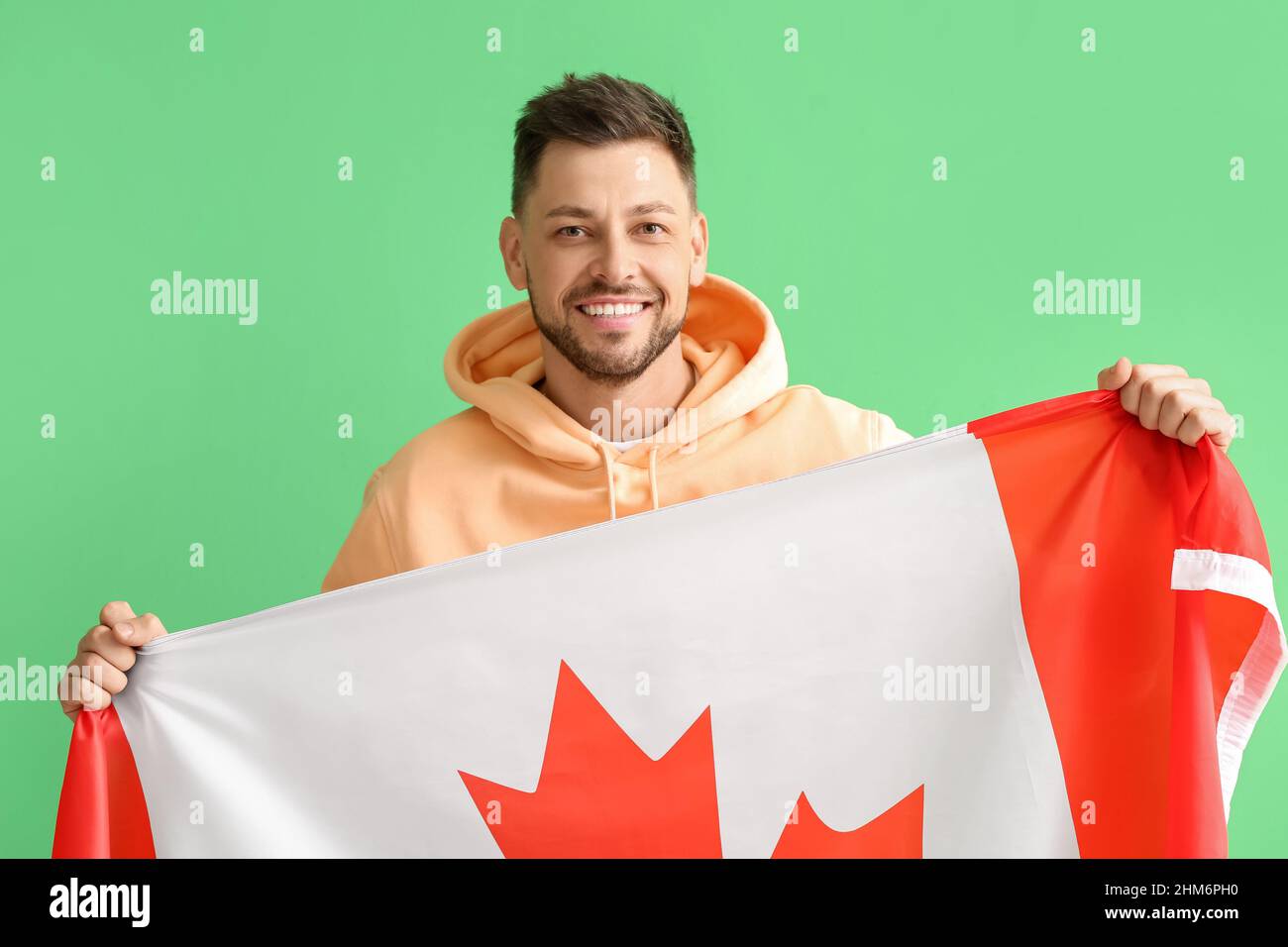 Happy young man with flag of Canada on green background Stock Photo - Alamy