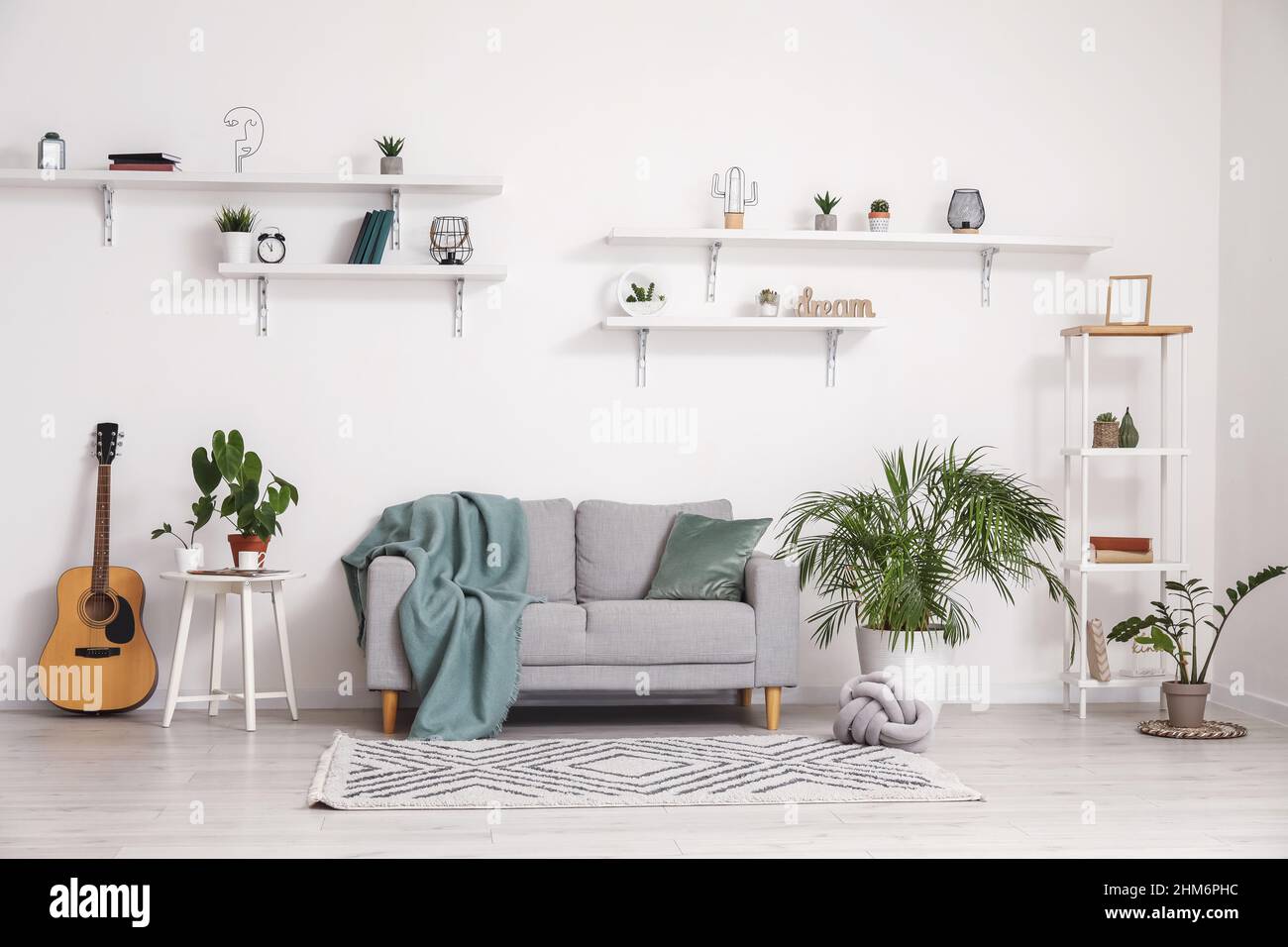 Interior of light living room with grey sofa, shelves and guitar Stock ...
