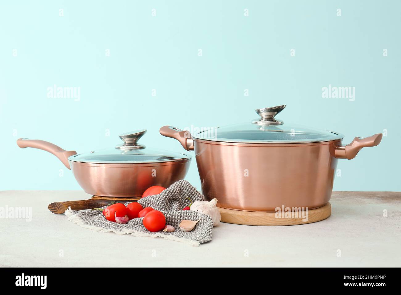 Shiny cooking pots with boards and food on table against blue ...