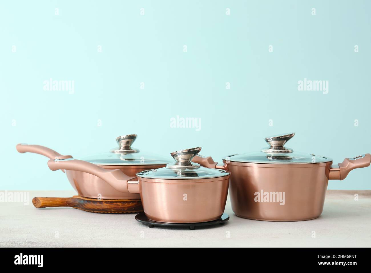 Shiny cooking pots with frying pan and board on table against blue ...