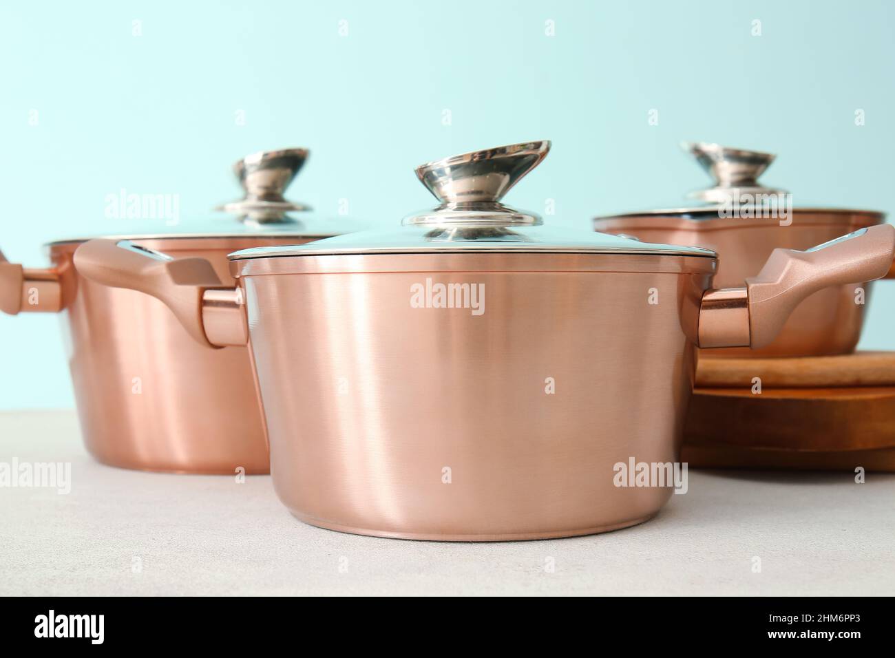 Shiny cooking pots with cutting boards on table against blue background ...