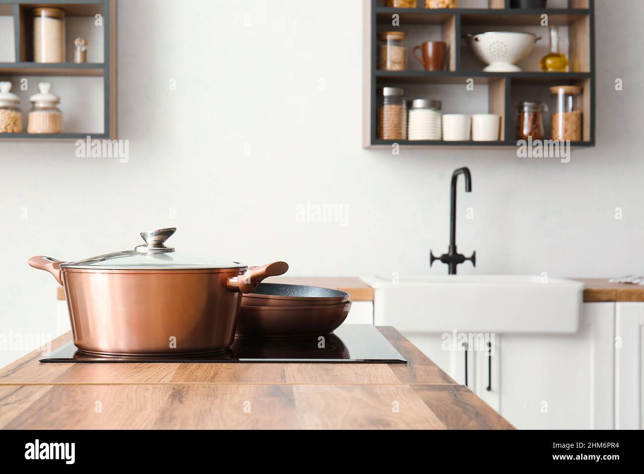 Shiny cooking pot and frying pans on stove in light kitchen Stock Photo ...