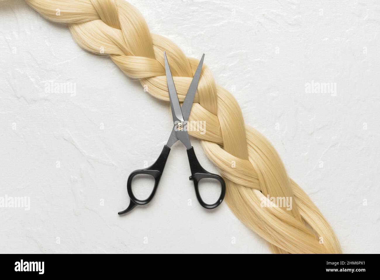Braided blonde hair for donation with scissors on white background Stock Photo - Alamy