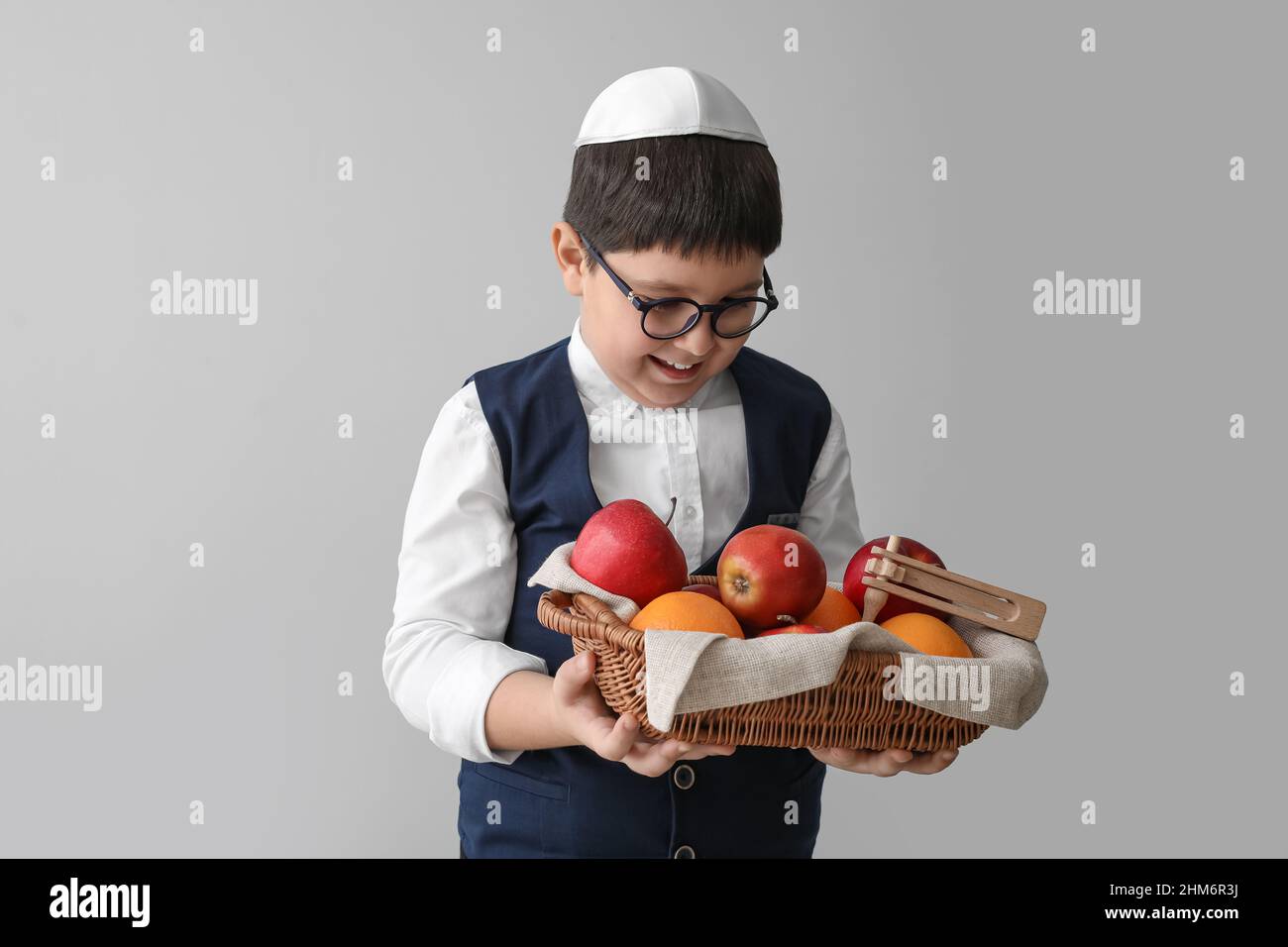 Little Jewish boy with gragger for Purim holiday and fruits in basket ...