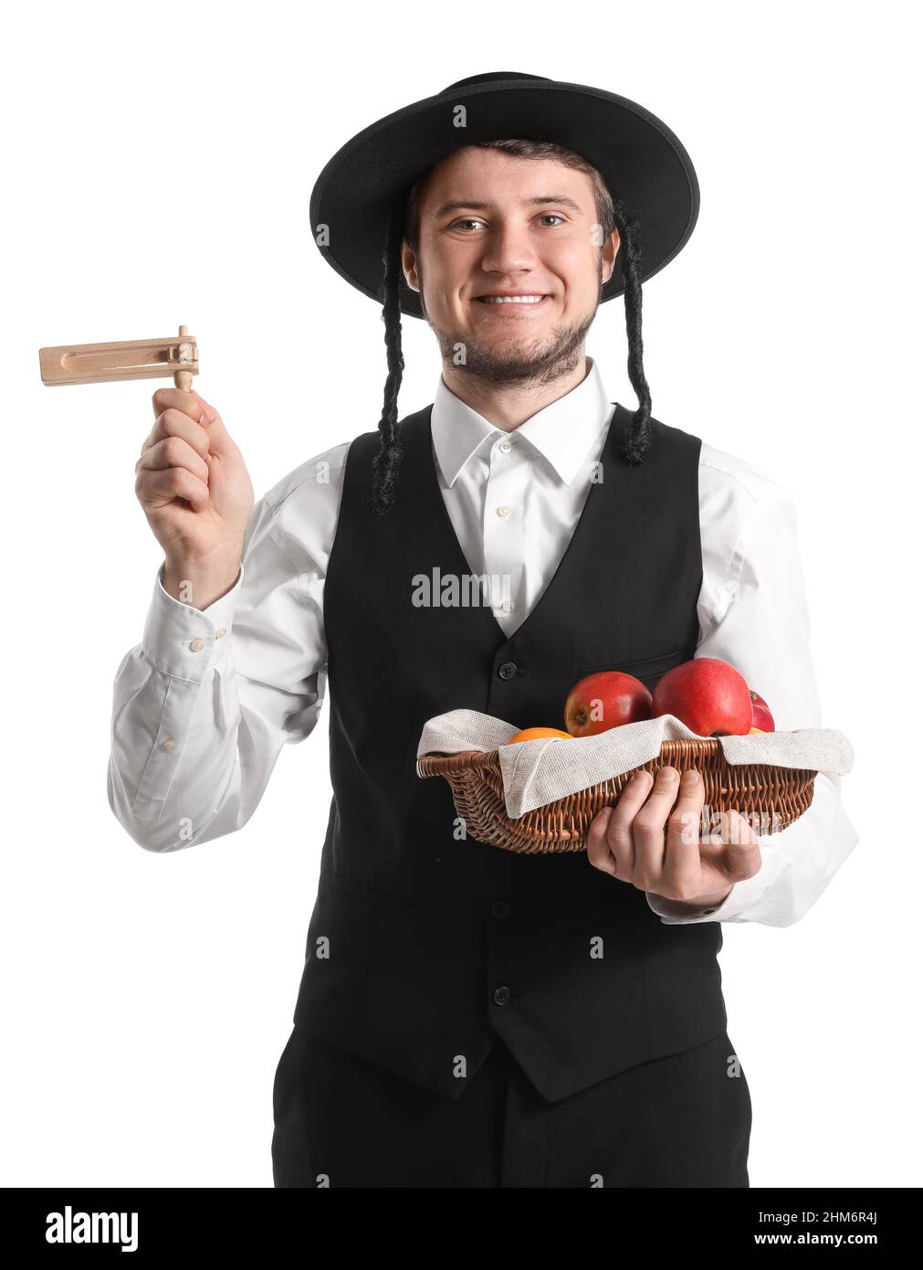Young Jewish man with gragger for Purim holiday and fruits in basket on ...
