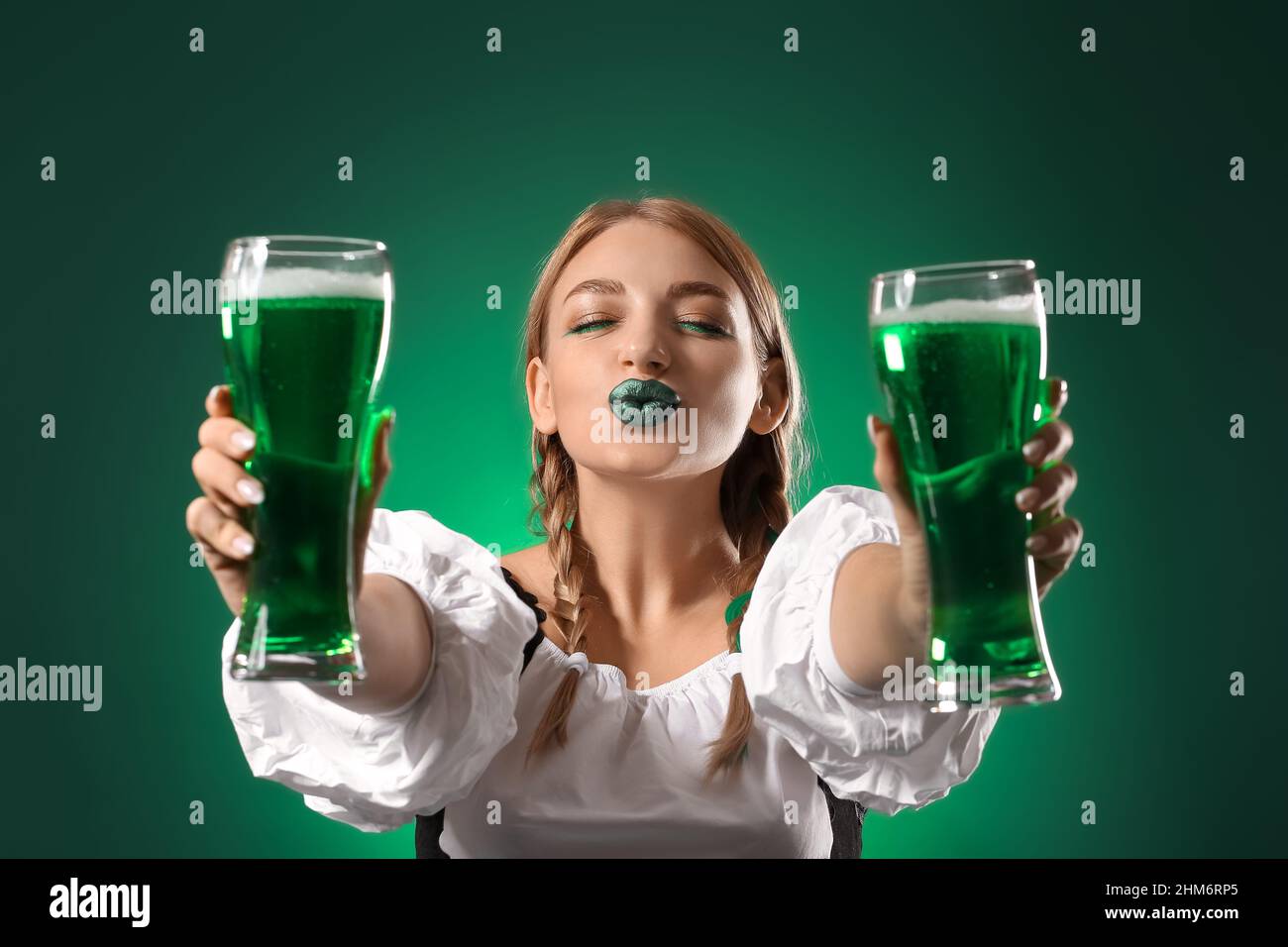 Beautiful Irish waitress with glasses of beer blowing kiss on green ...
