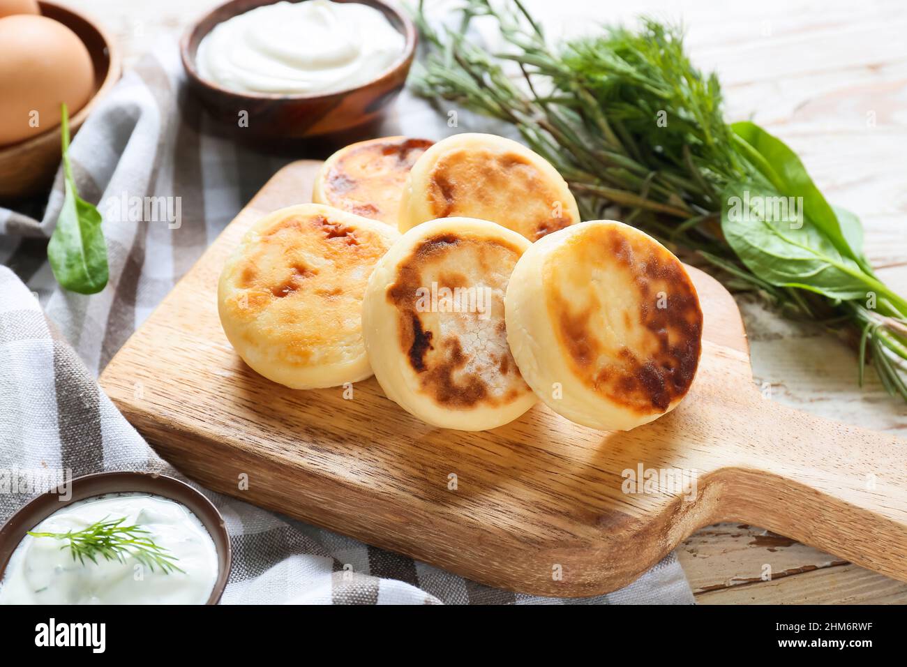 Board with tasty cottage cheese pancakes and sauce on table, closeup ...