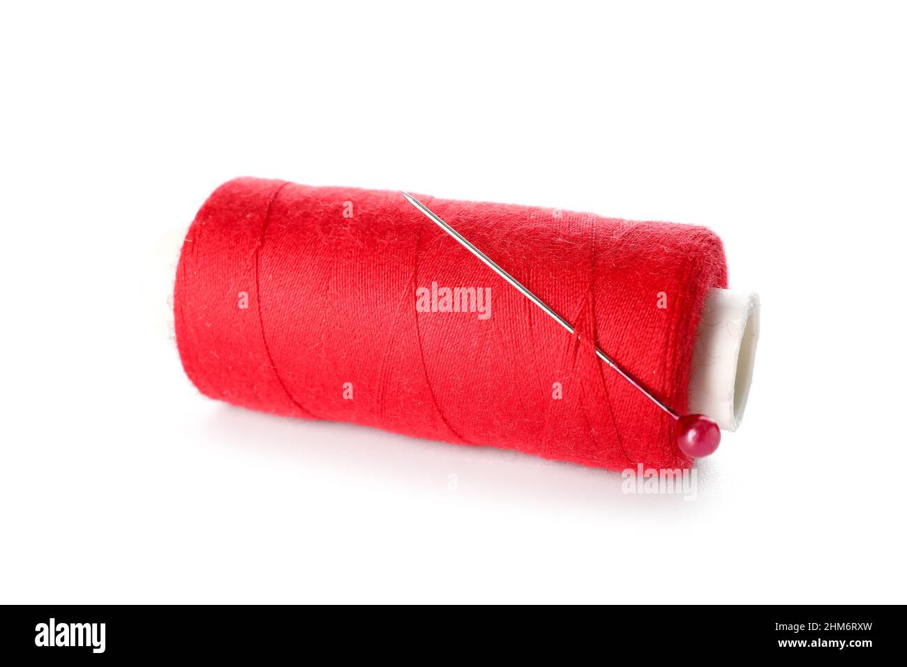Red sewing thread spool with needle on white background Stock Photo - Alamy