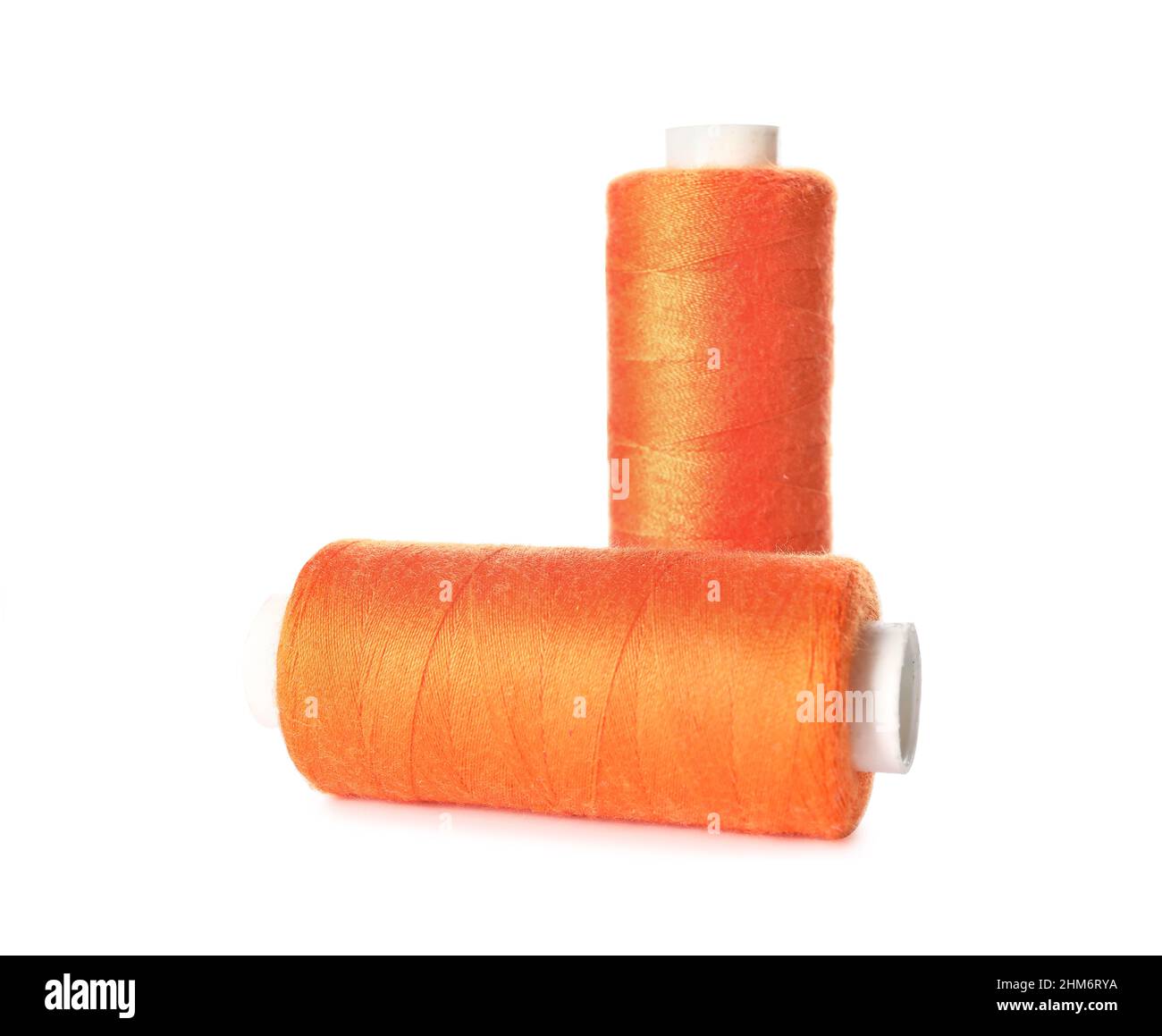 Orange sewing threads on white background Stock Photo - Alamy