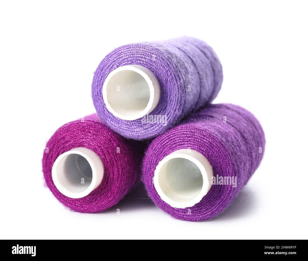Purple sewing threads on white background Stock Photo - Alamy