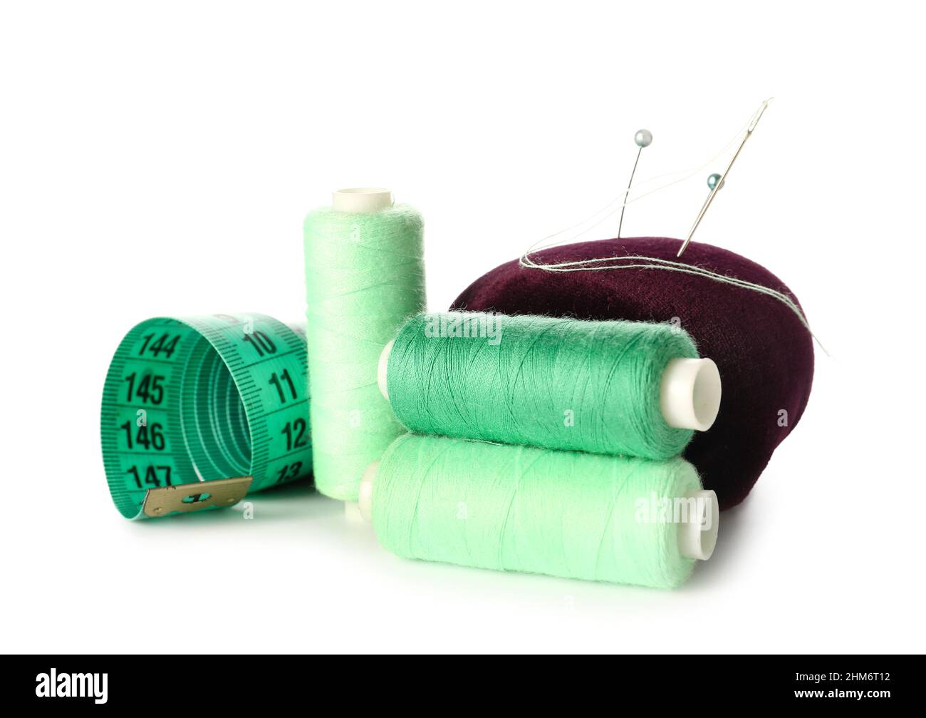 Sewing threads with needles and measuring tape on white background ...