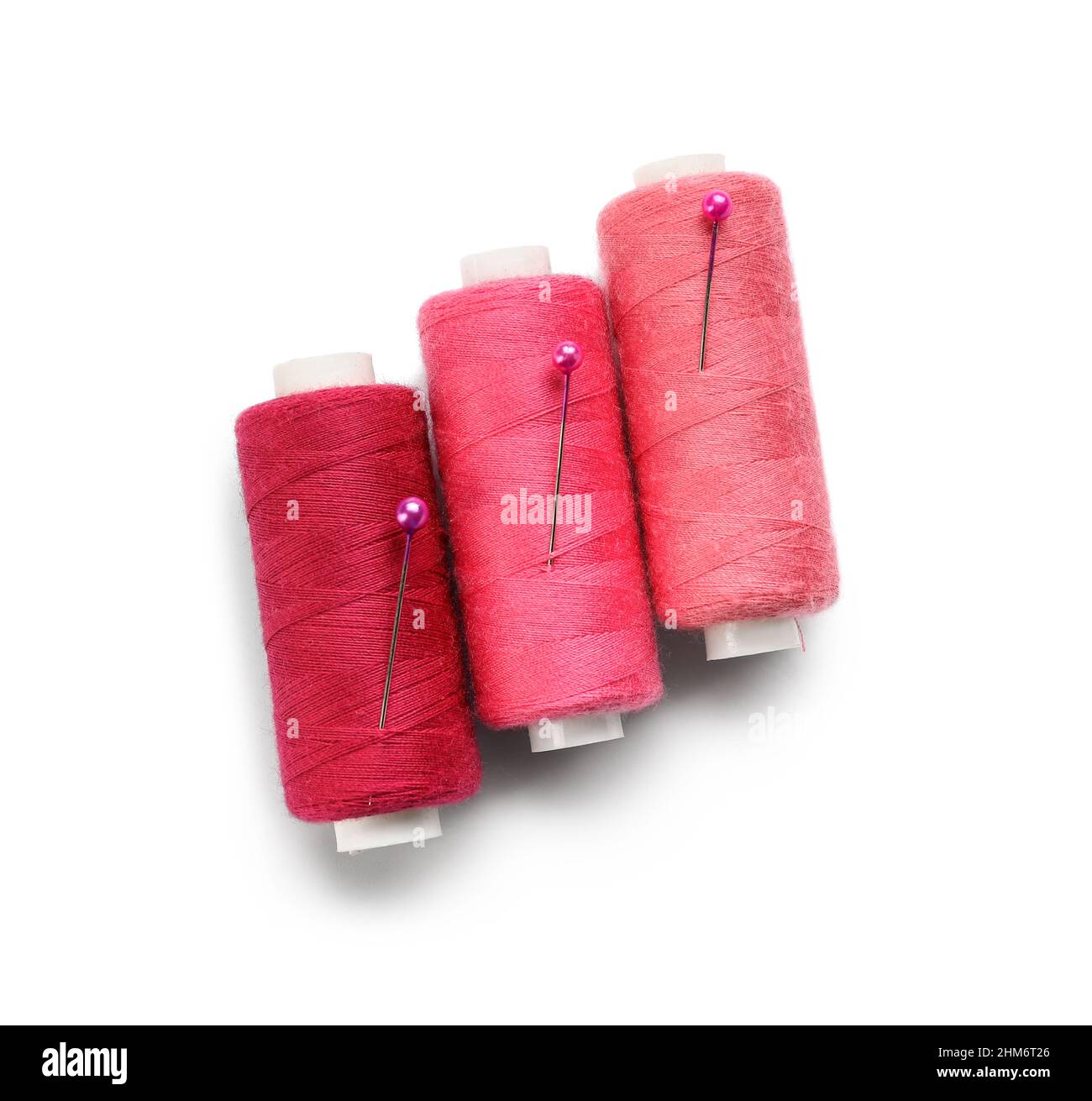 Pink sewing threads on white background Stock Photo - Alamy