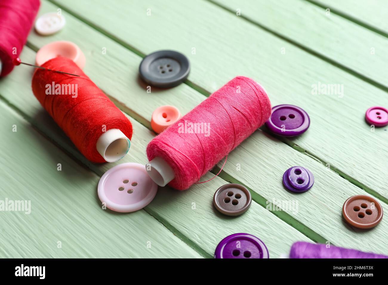 Sewing threads with buttons on color wooden background Stock Photo - Alamy