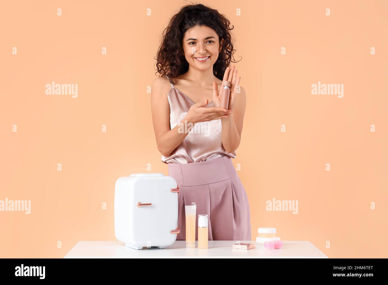 Beautiful smiling woman holding bottle of perfume near table with ...