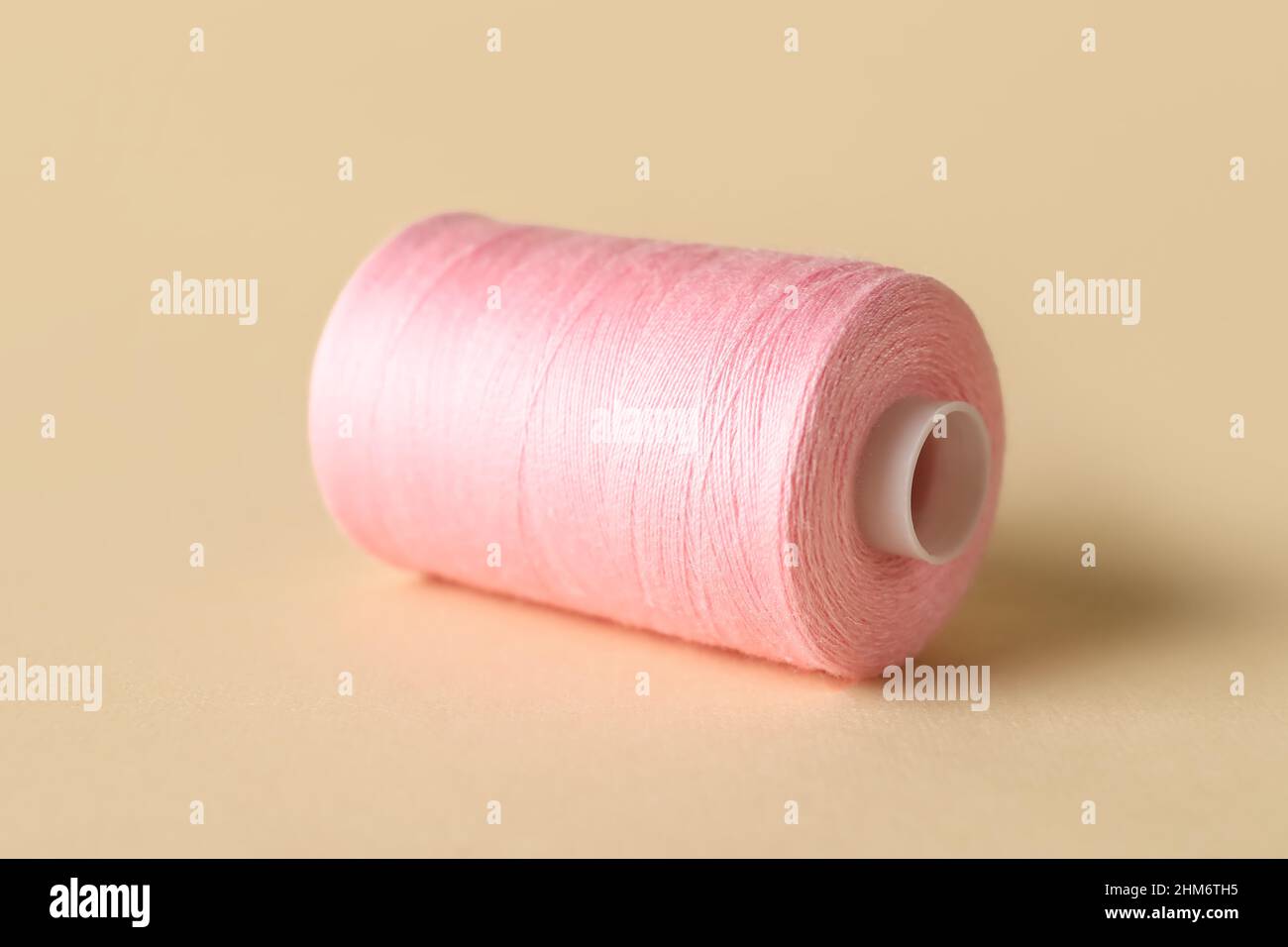 Pink sewing thread spool on light background Stock Photo - Alamy