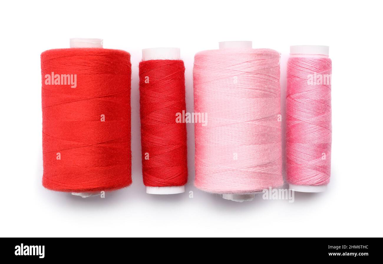 Red and pink sewing thread spools on white background Stock Photo - Alamy