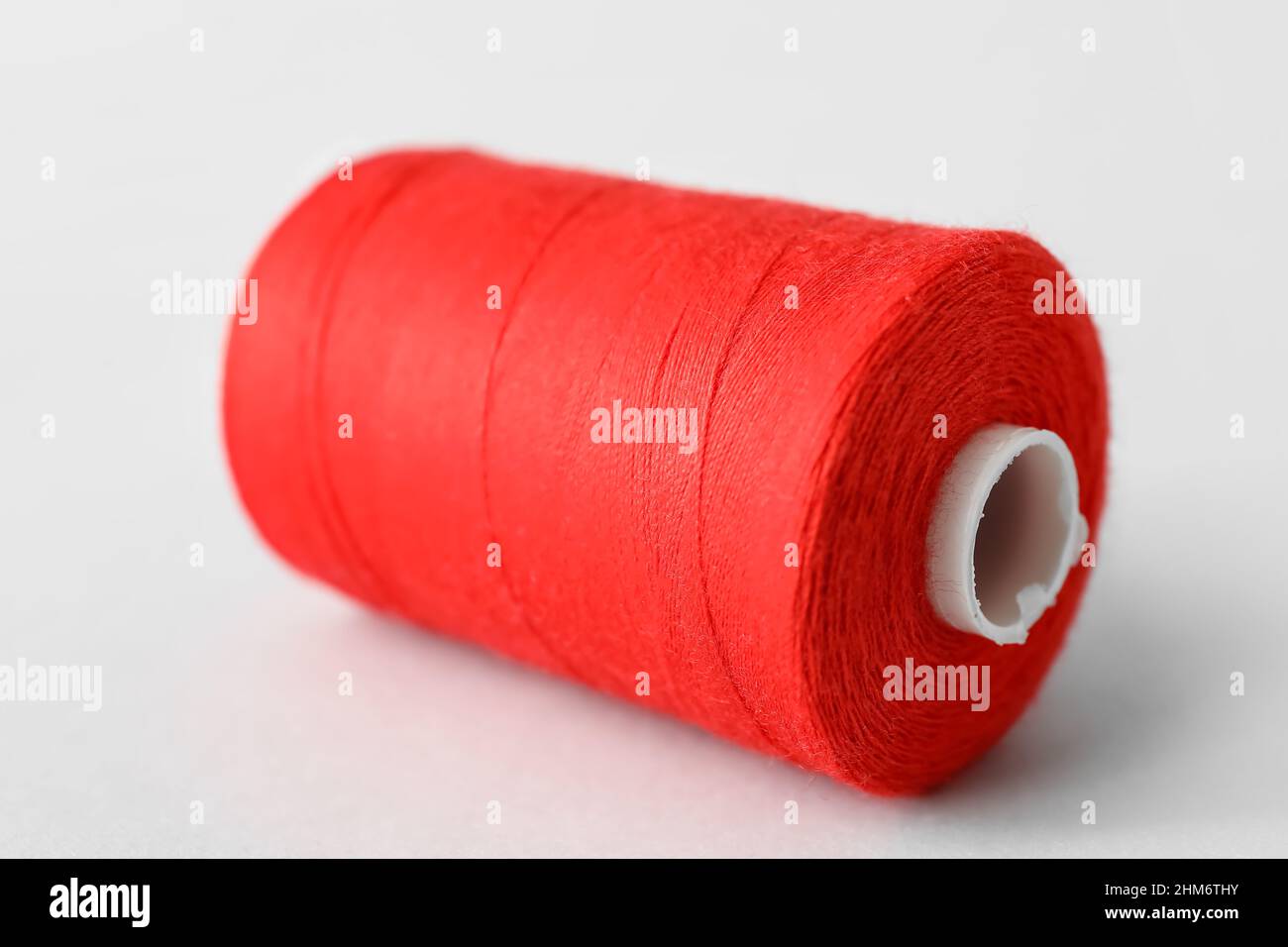 Red sewing thread spool on light background Stock Photo - Alamy
