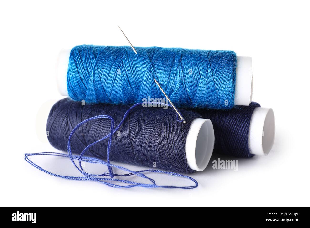 Blue sewing thread spools and needle on white background Stock Photo ...