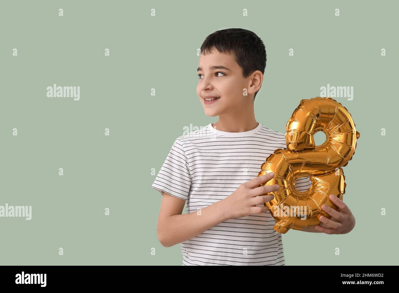 Little boy with balloon in shape of figure 8 on green background ...