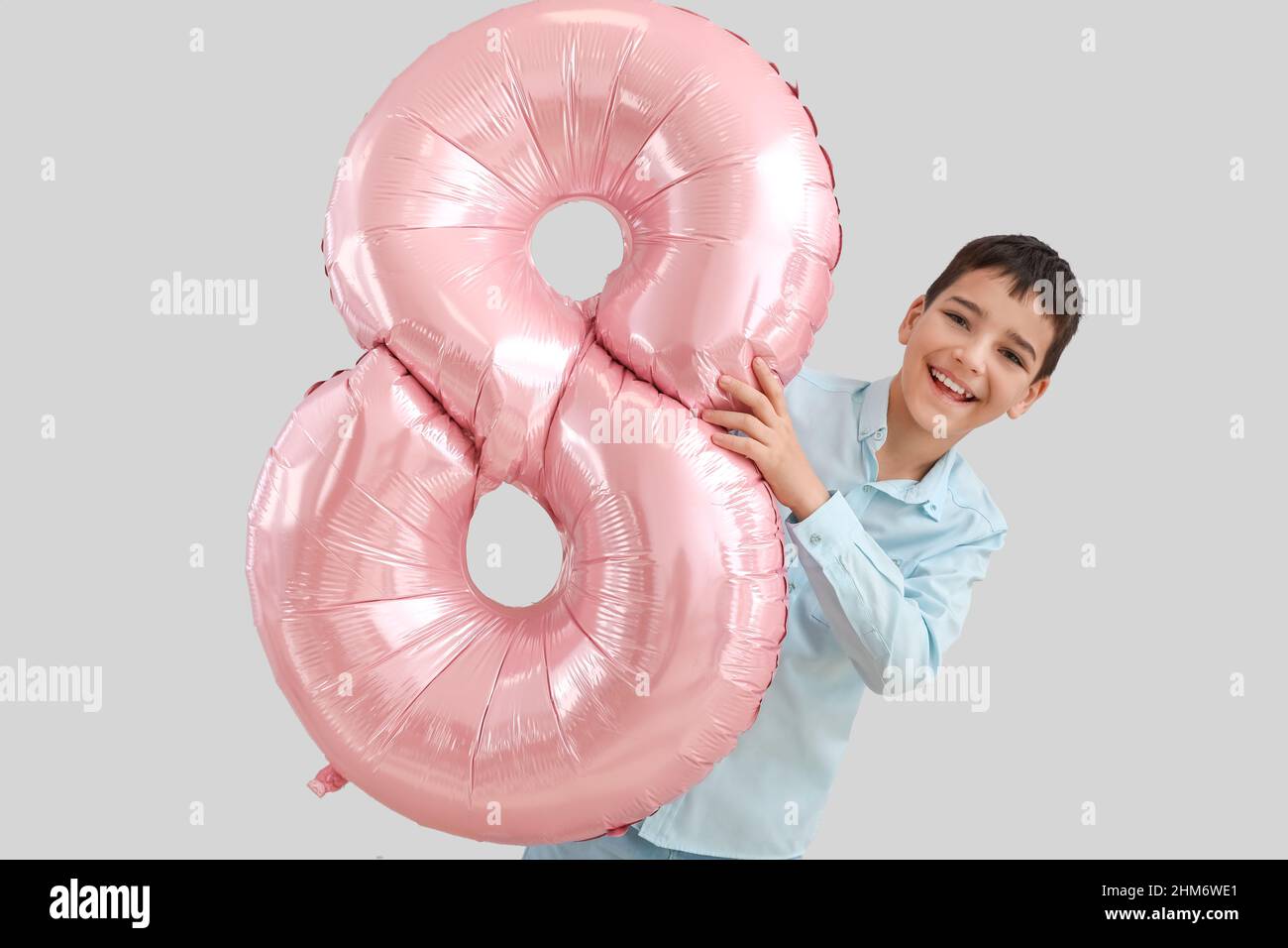 Little boy with big balloon in shape of figure 8 on light background ...