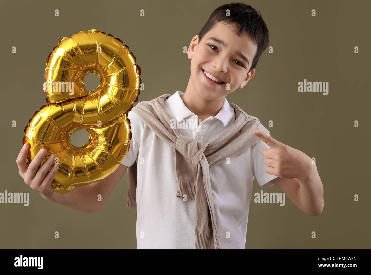 Little boy pointing at balloon in shape of figure 8 on color background ...