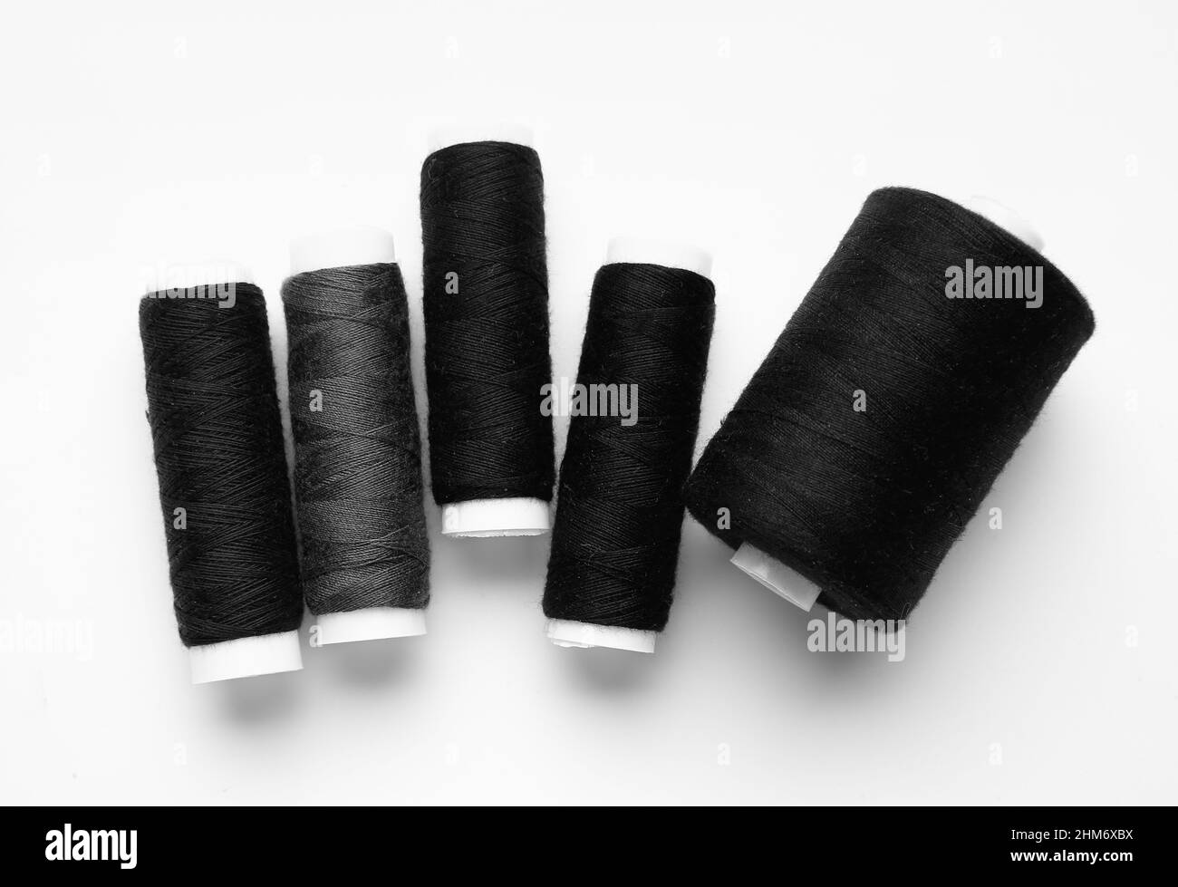 Black thread spools on white background Stock Photo - Alamy