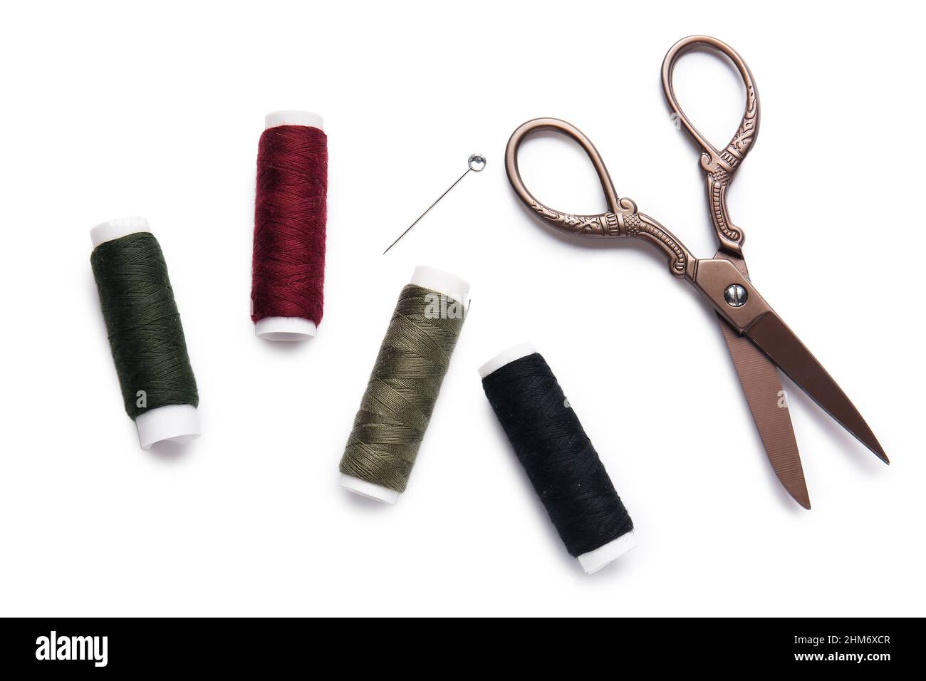 Thread spools with scissors and needle on white background Stock Photo ...