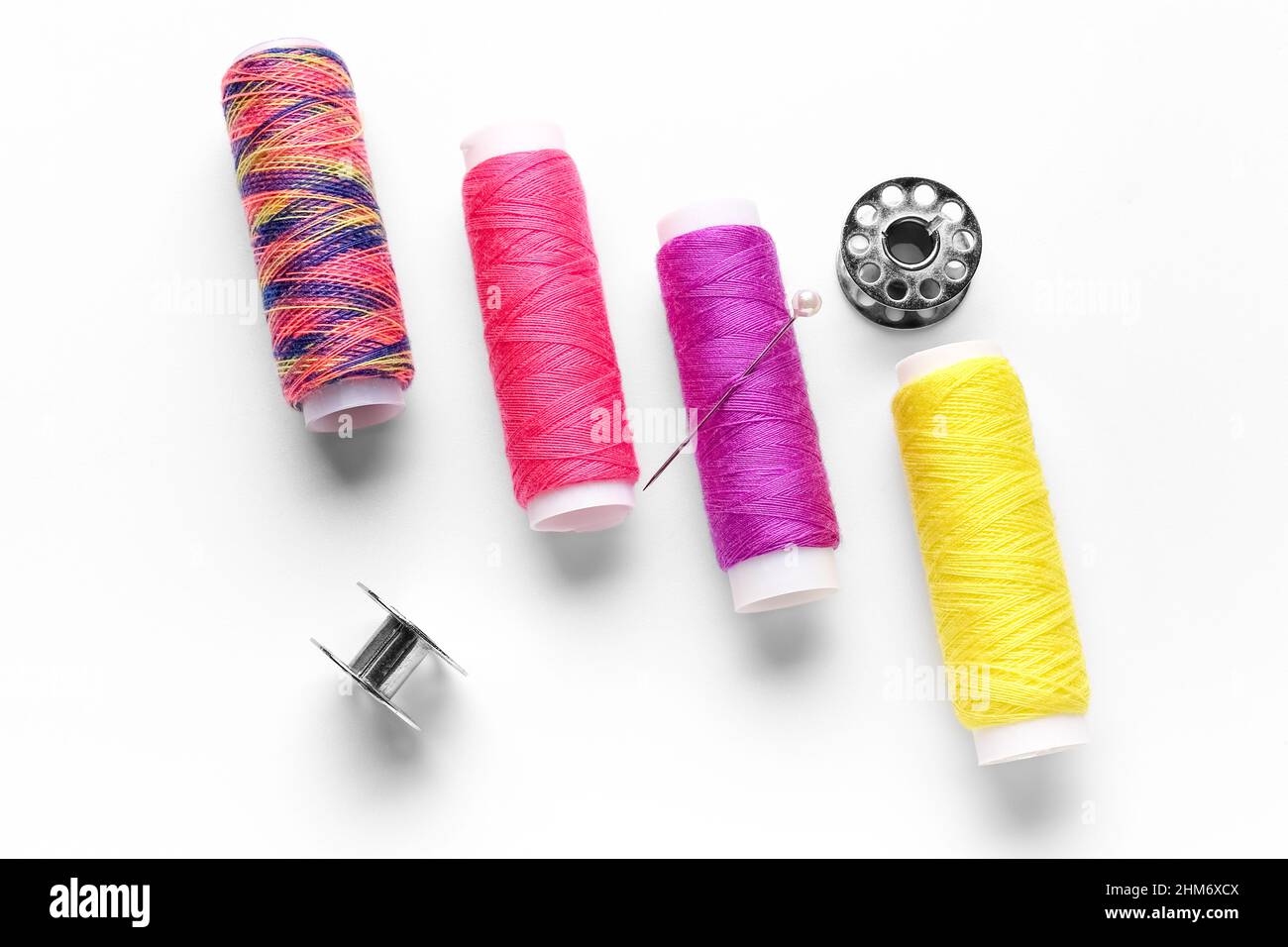Thread spools and needle on white background Stock Photo - Alamy
