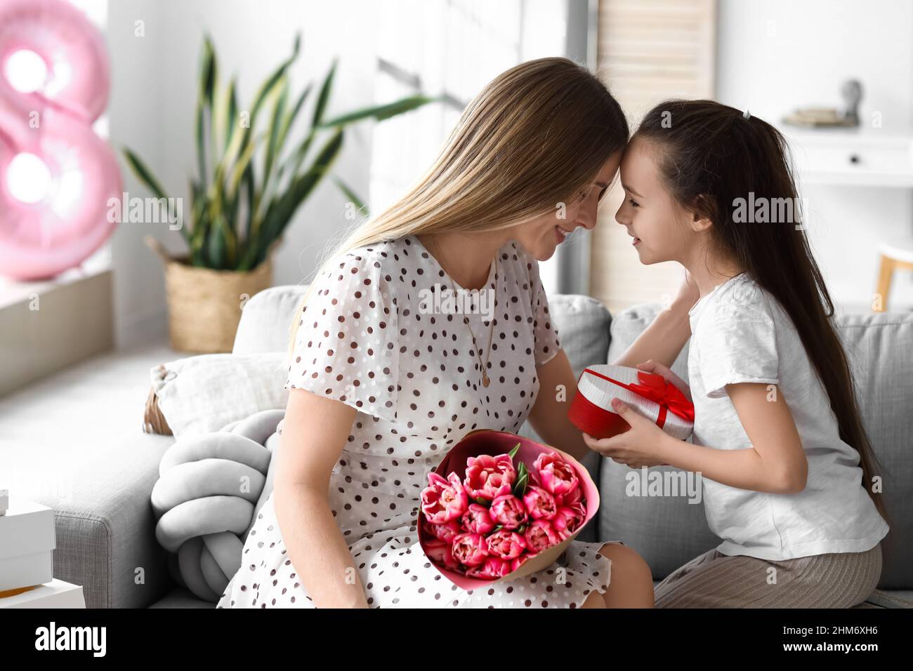 Little girl greeting her mother with gift at home on International ...