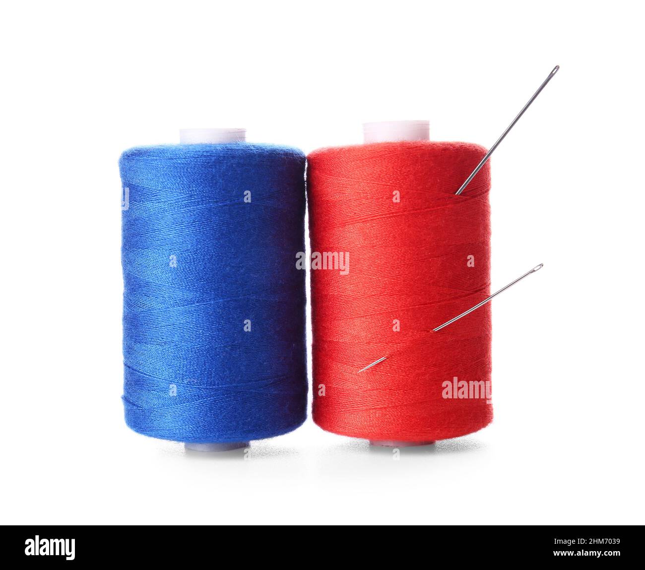 Red and blue thread spools with needles on white background Stock Photo ...