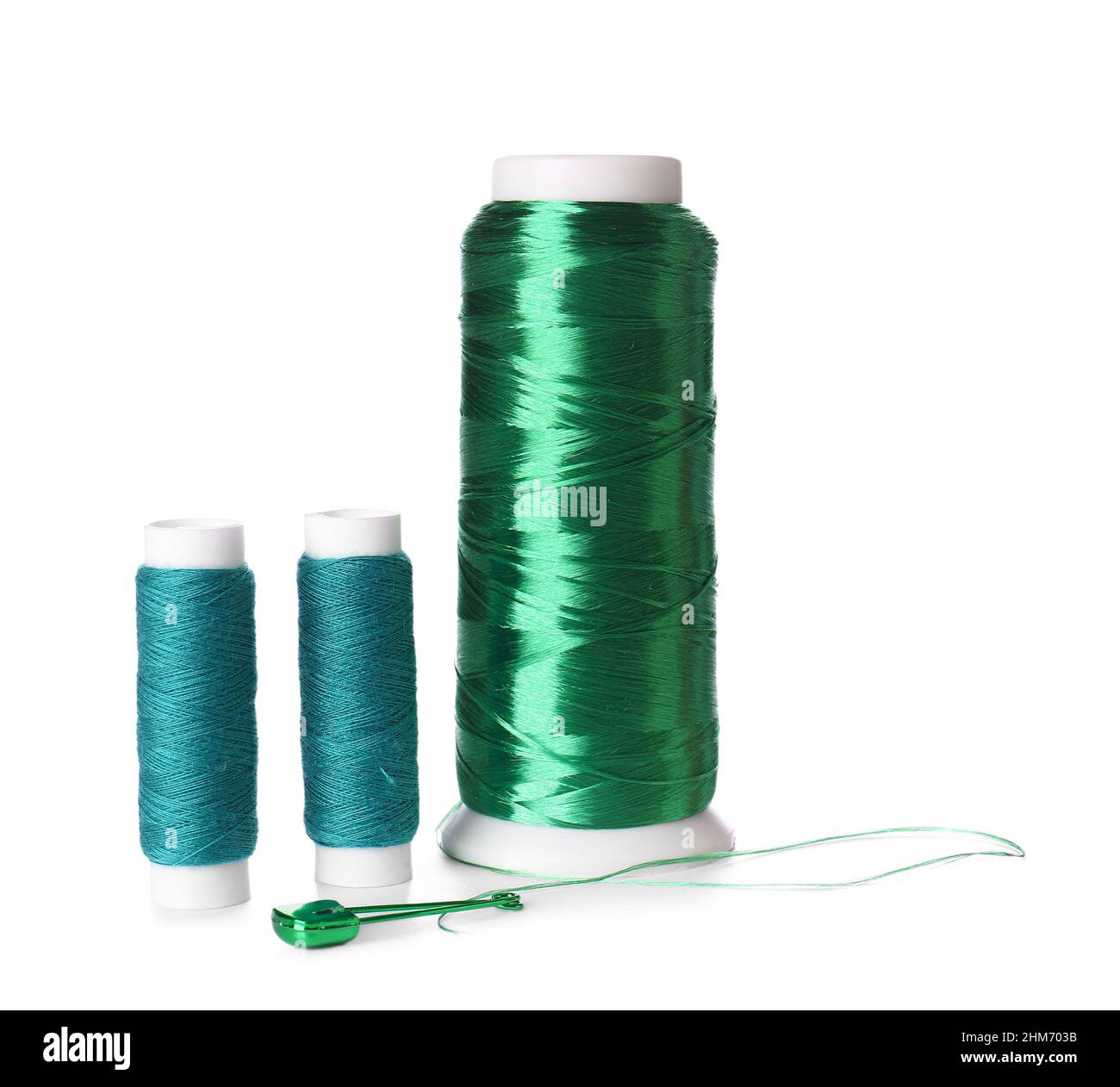 Green thread spools and safety pin on white background Stock Photo - Alamy
