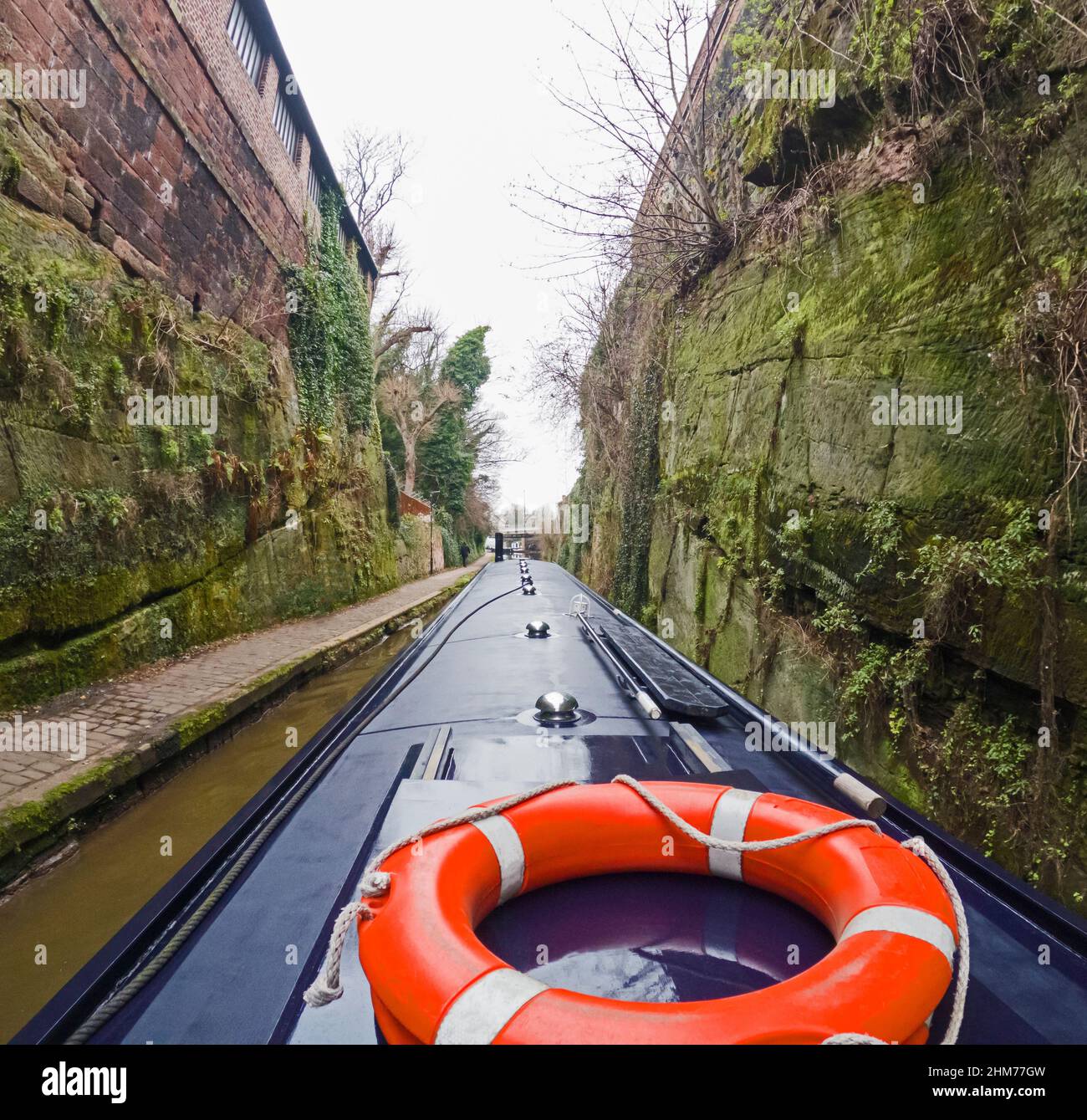 View from a narrowboat travelling through cutting in English rural ...