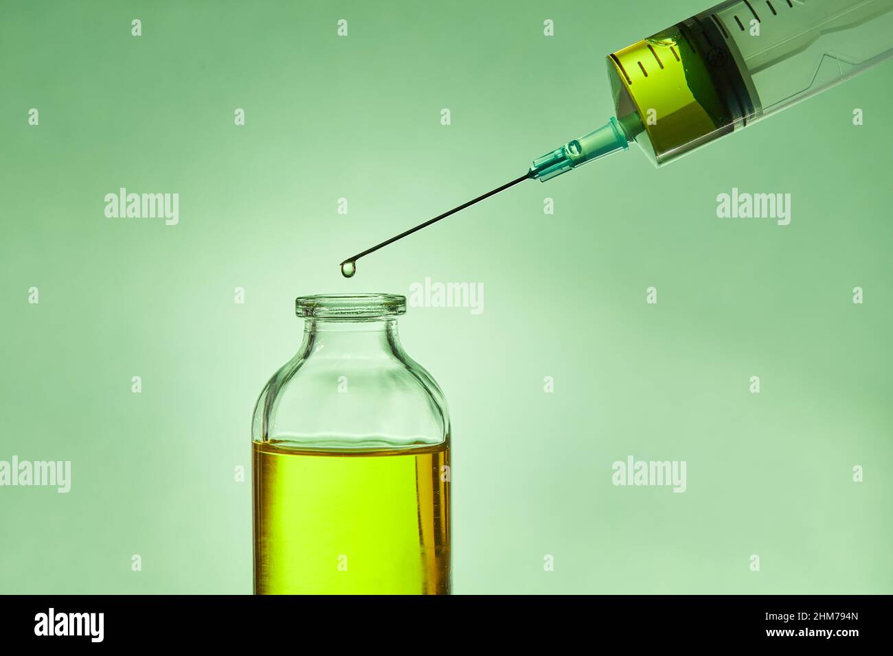 A drop of liquid drips from the needle of a medical syringe into the ...
