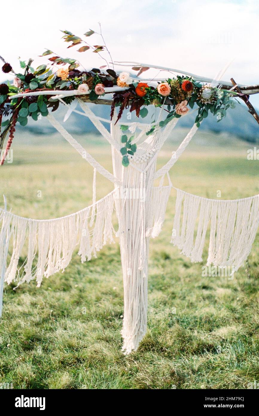 White macrame and red flowers on rustic wedding arch Stock Photo - Alamy