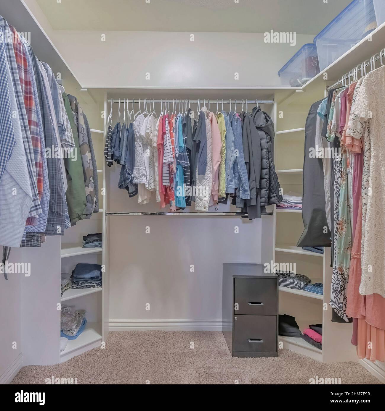 Square Interior of a walk in closet with shelving units and clothes ...