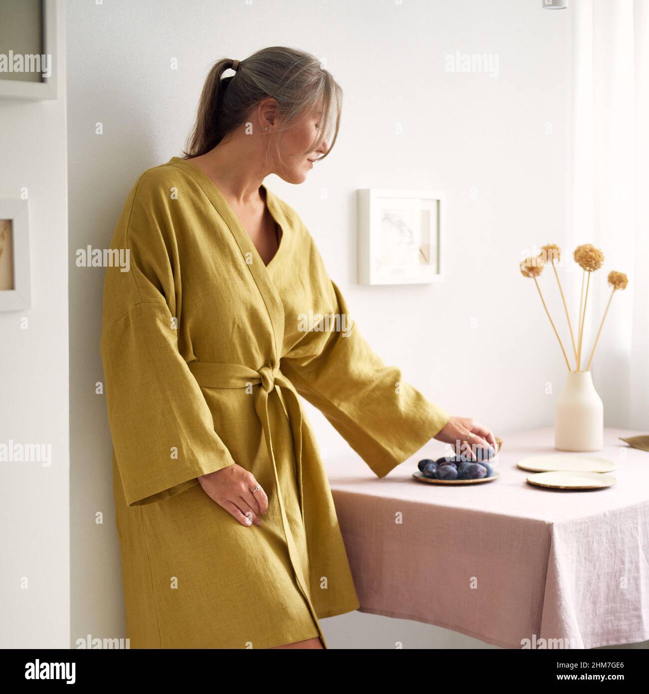 Young girl in a dressing gown lays the table. Natural fabrics and ...