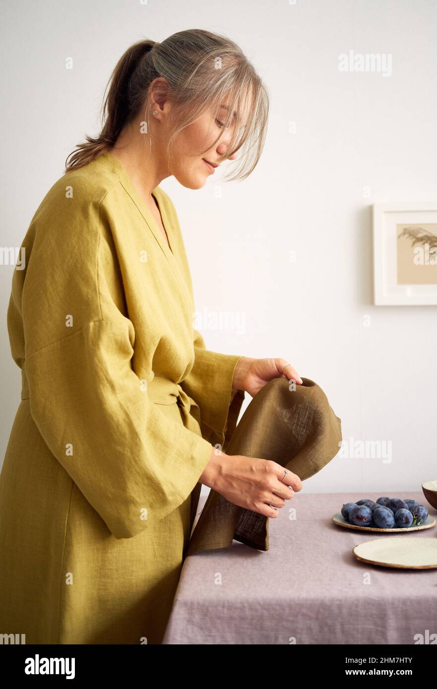 Young girl in a dressing gown lays the table. Natural fabrics and ...