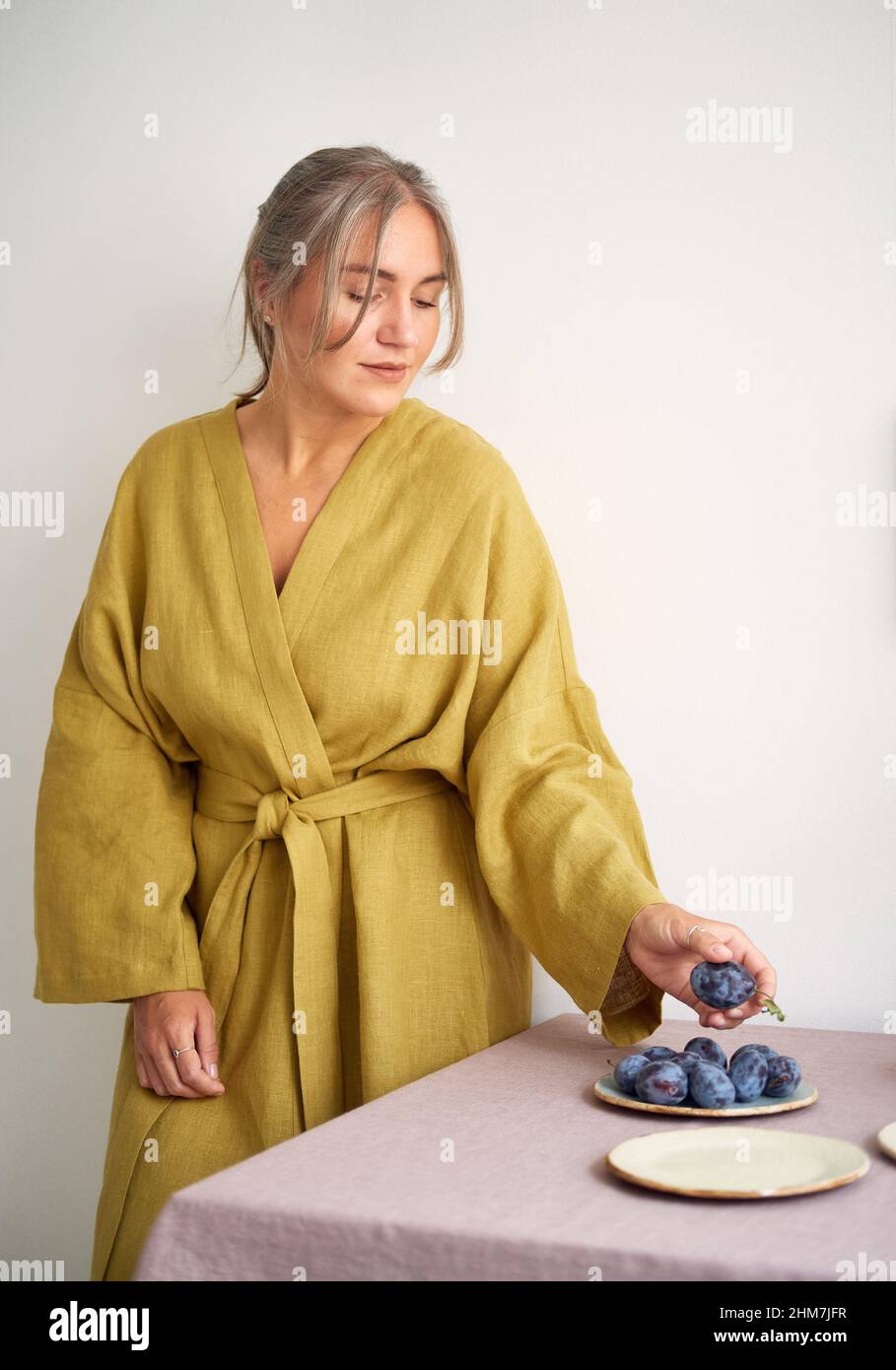 Young girl in a dressing gown lays the table. Natural fabrics and ...