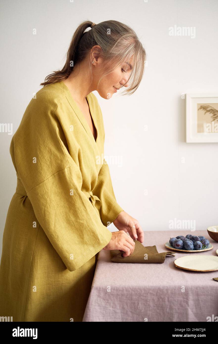 Young girl in a dressing gown lays the table. Natural fabrics and ...