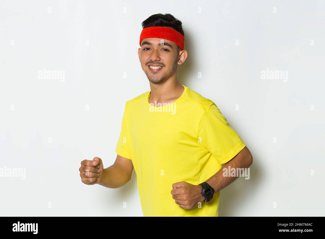 young sporty man dressed in yellow tshirt running on white background ...