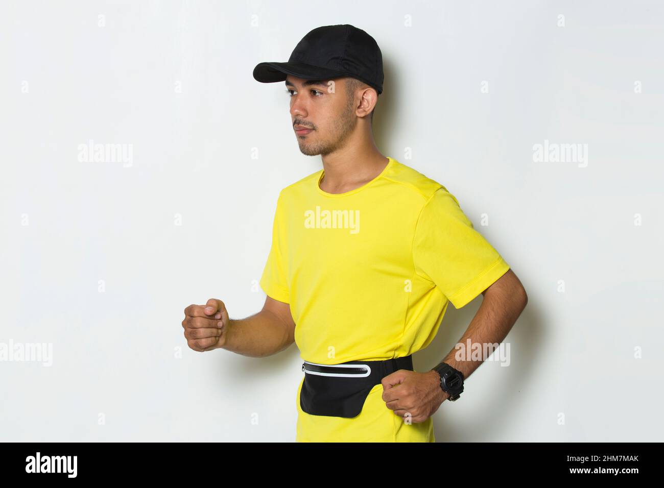 young sporty man dressed in yellow tshirt running on white background ...