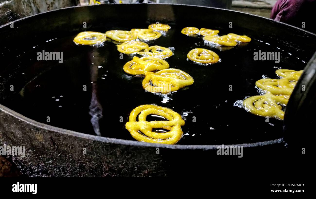 An Indian jalebi frying in oil pan at stall. Jalebi is a famous indian ...